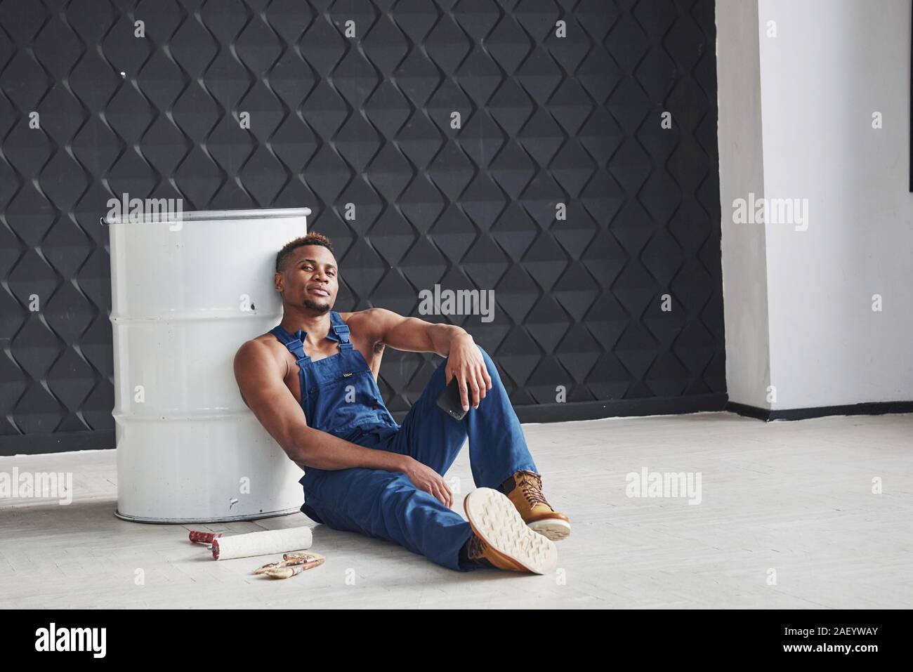 Some rest time. African american man sits on the floor and leaning to ...