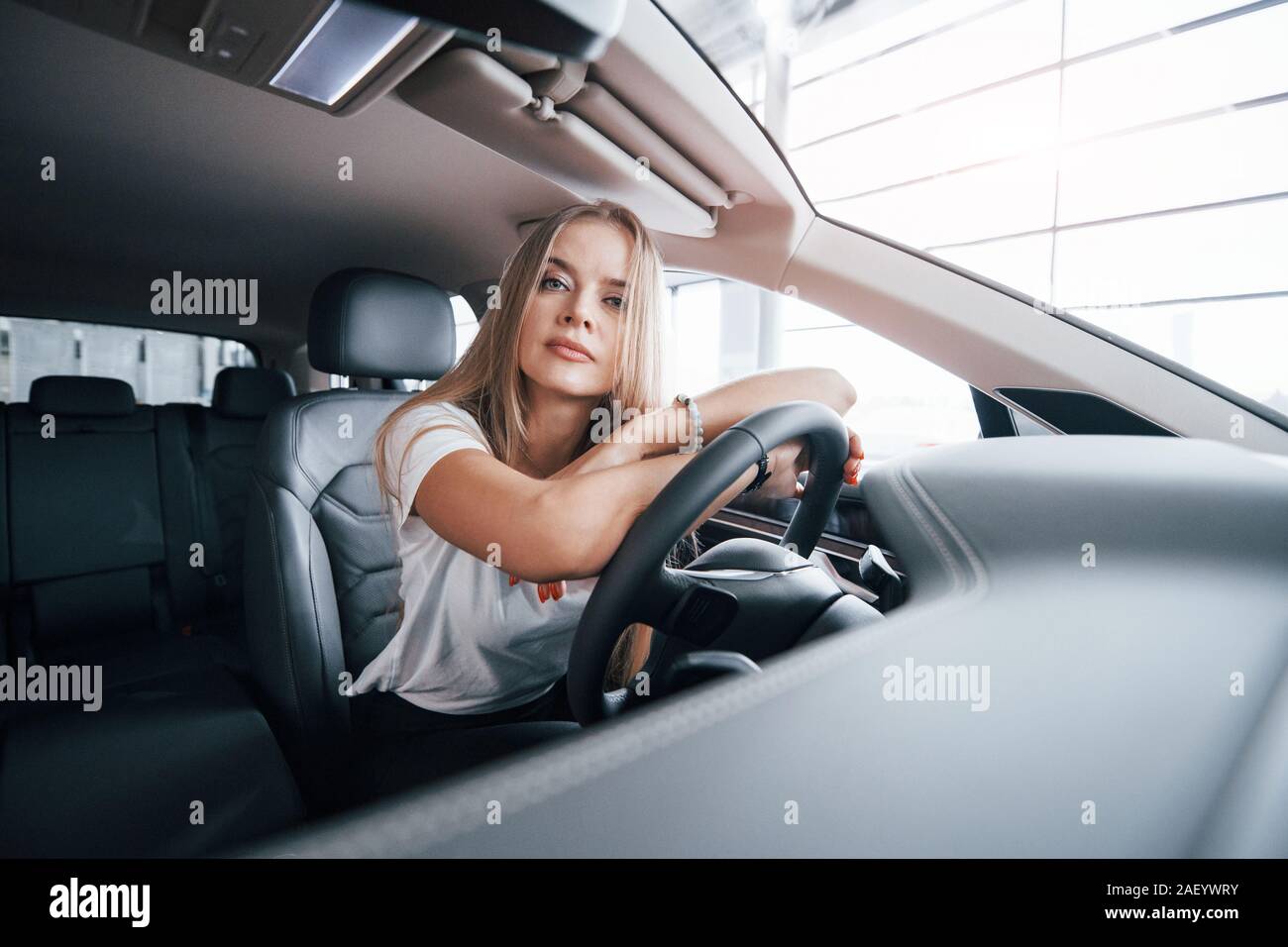 Looking forward. Girl in modern car in the salon. At daytime indoors ...