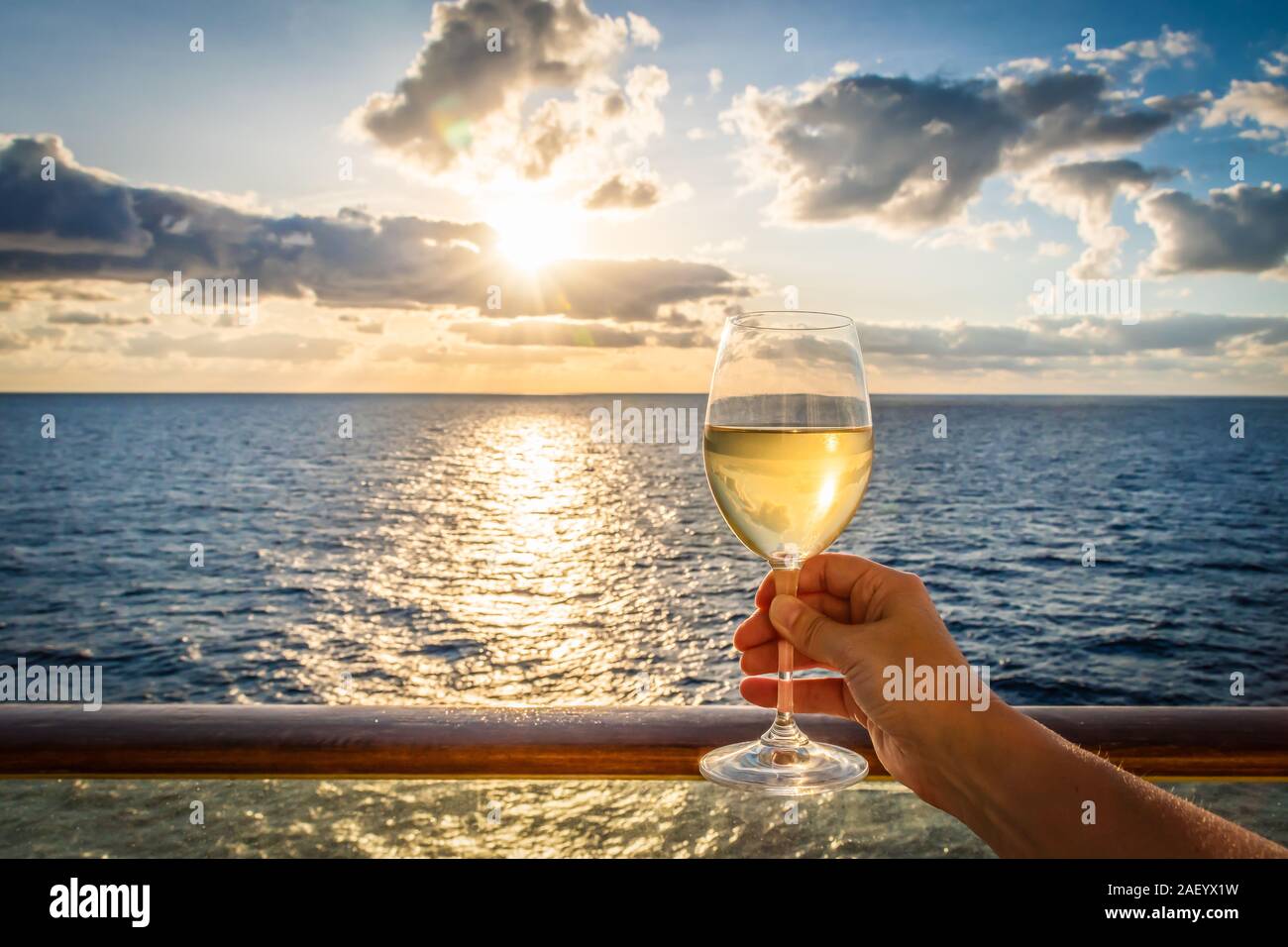 During sunset a female hand toasts the new year with a glass of white ...