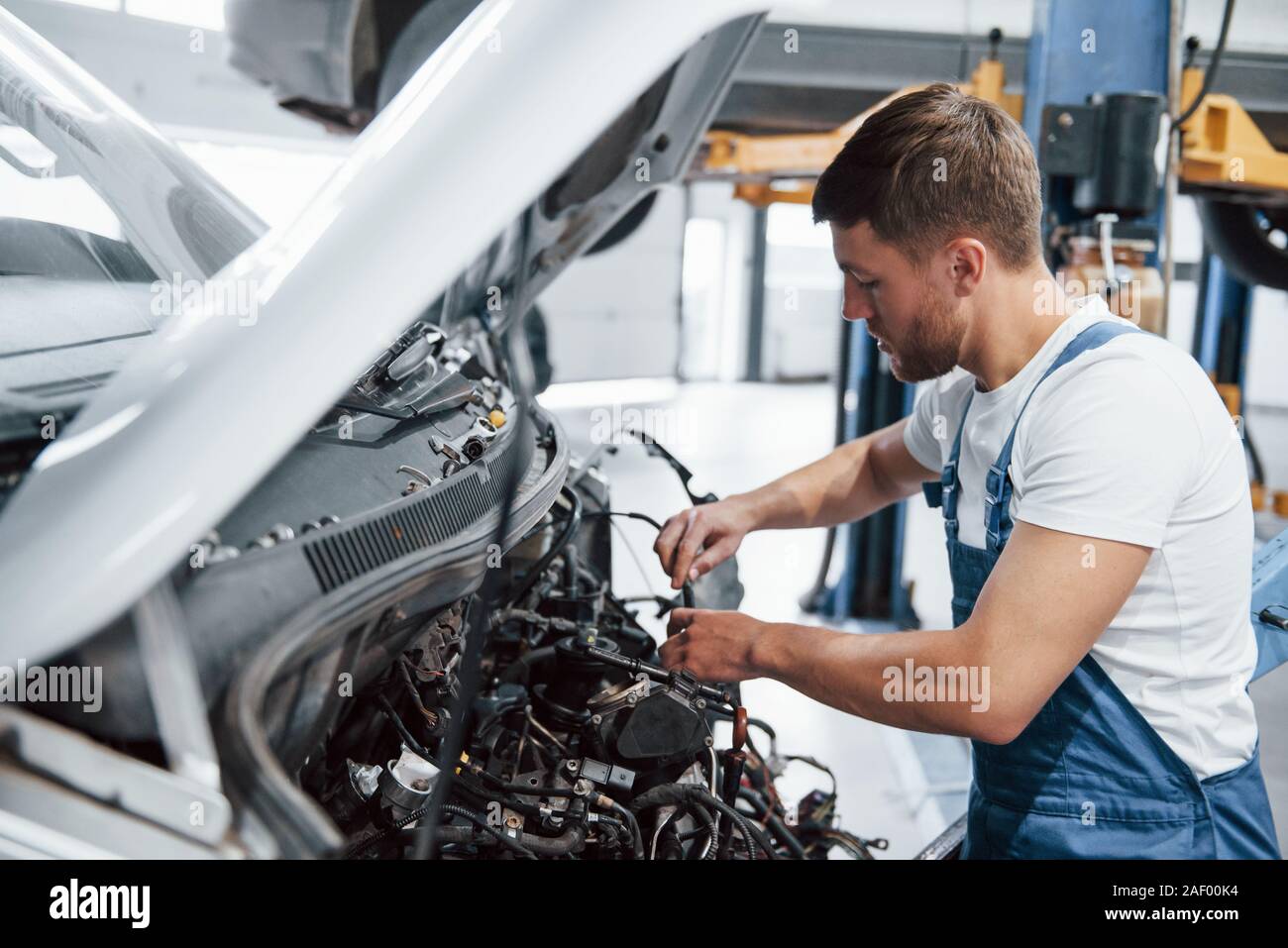 Broken car. Employee in the blue colored uniform works in the ...