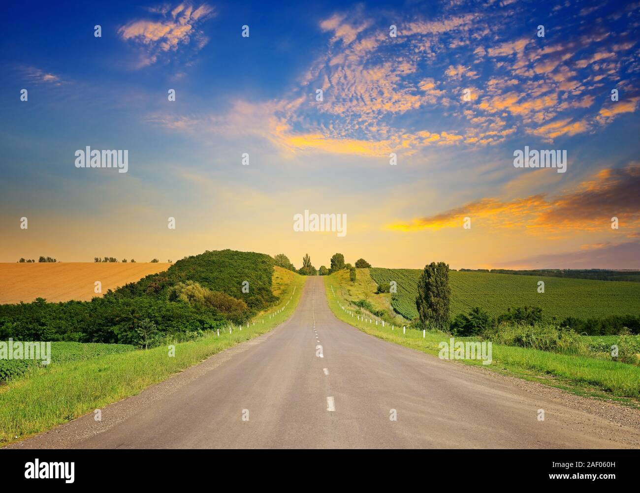 Sunrise over picturesque landscape. Straight road and fields ...