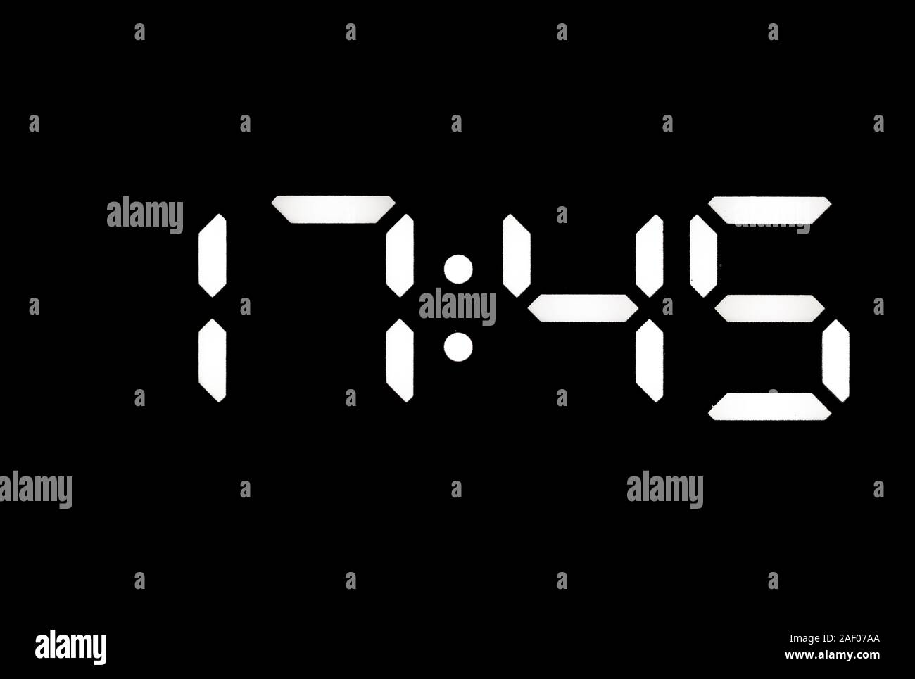 Real white led digital clock on a black background showing time 17:45 ...