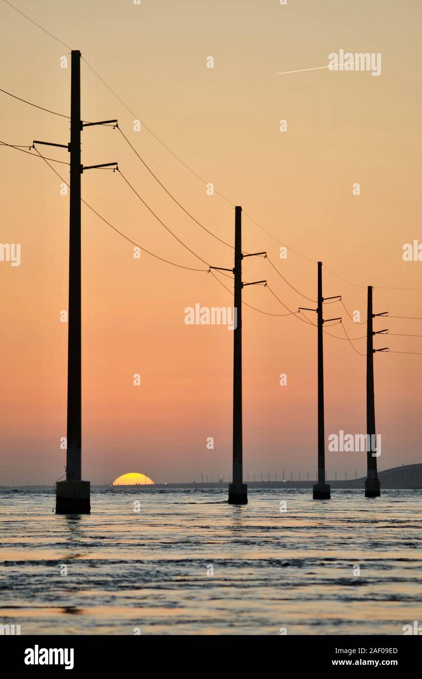 Electrical power lines above the Atlantic Ocean, silhouetted, during ...