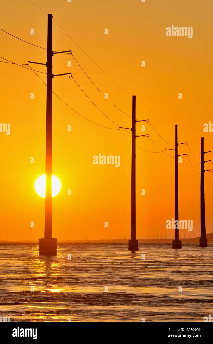 Electrical power lines above the Atlantic Ocean, silhouetted, during ...