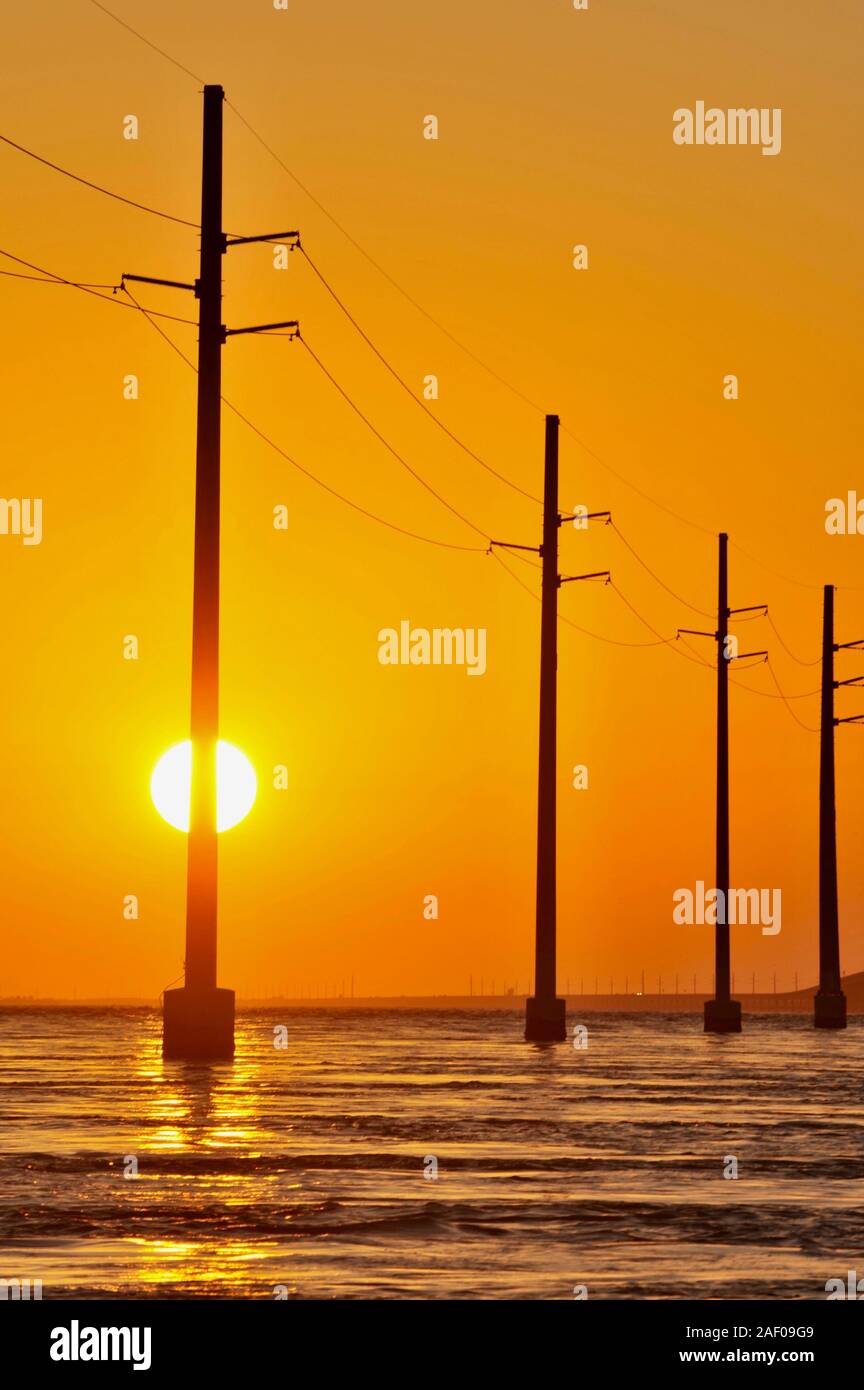 Electrical power lines above the Atlantic Ocean, silhouetted, during ...