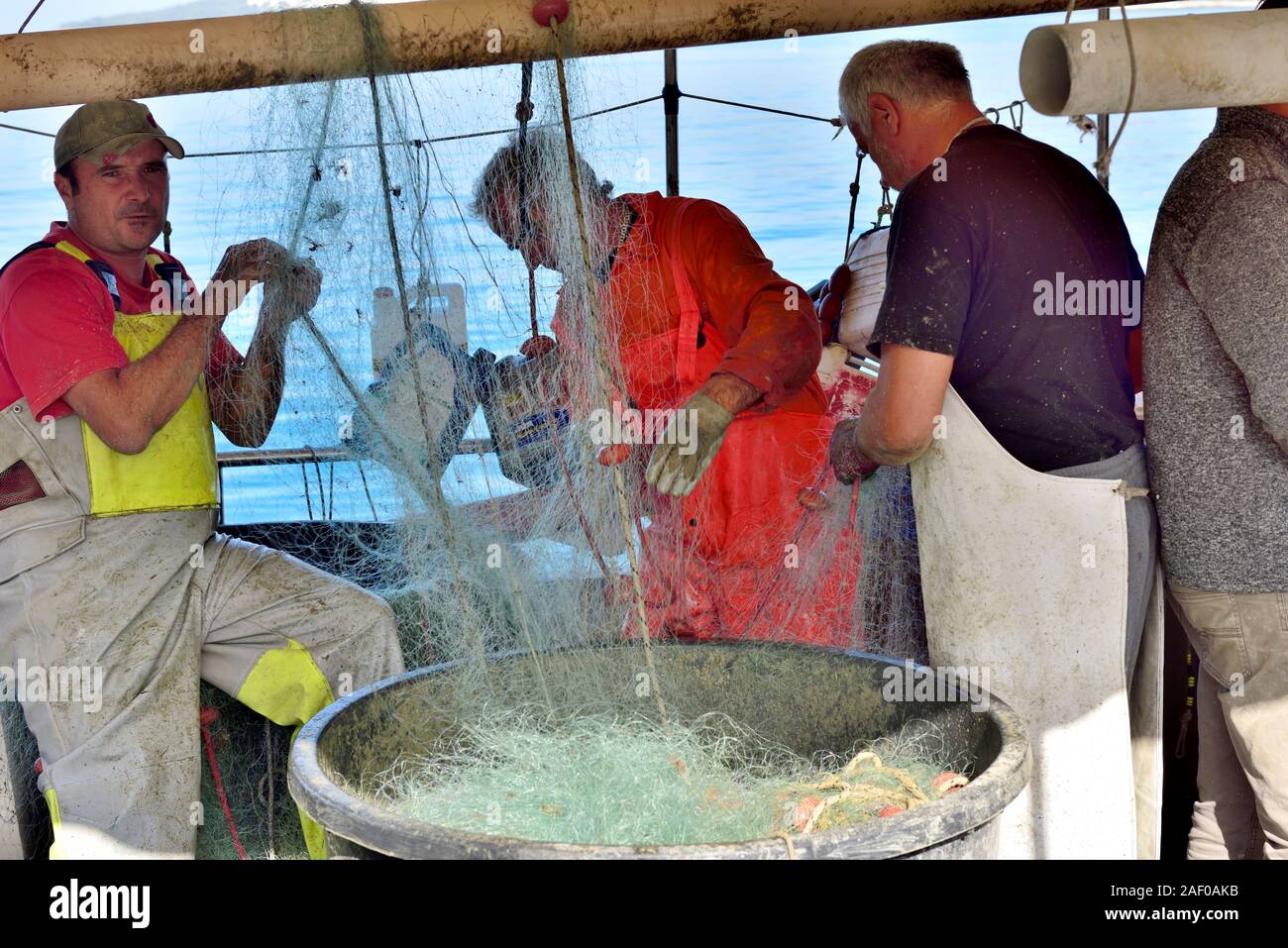 Fishermen cleaning and mending nets on fishing boat out of historic old ...