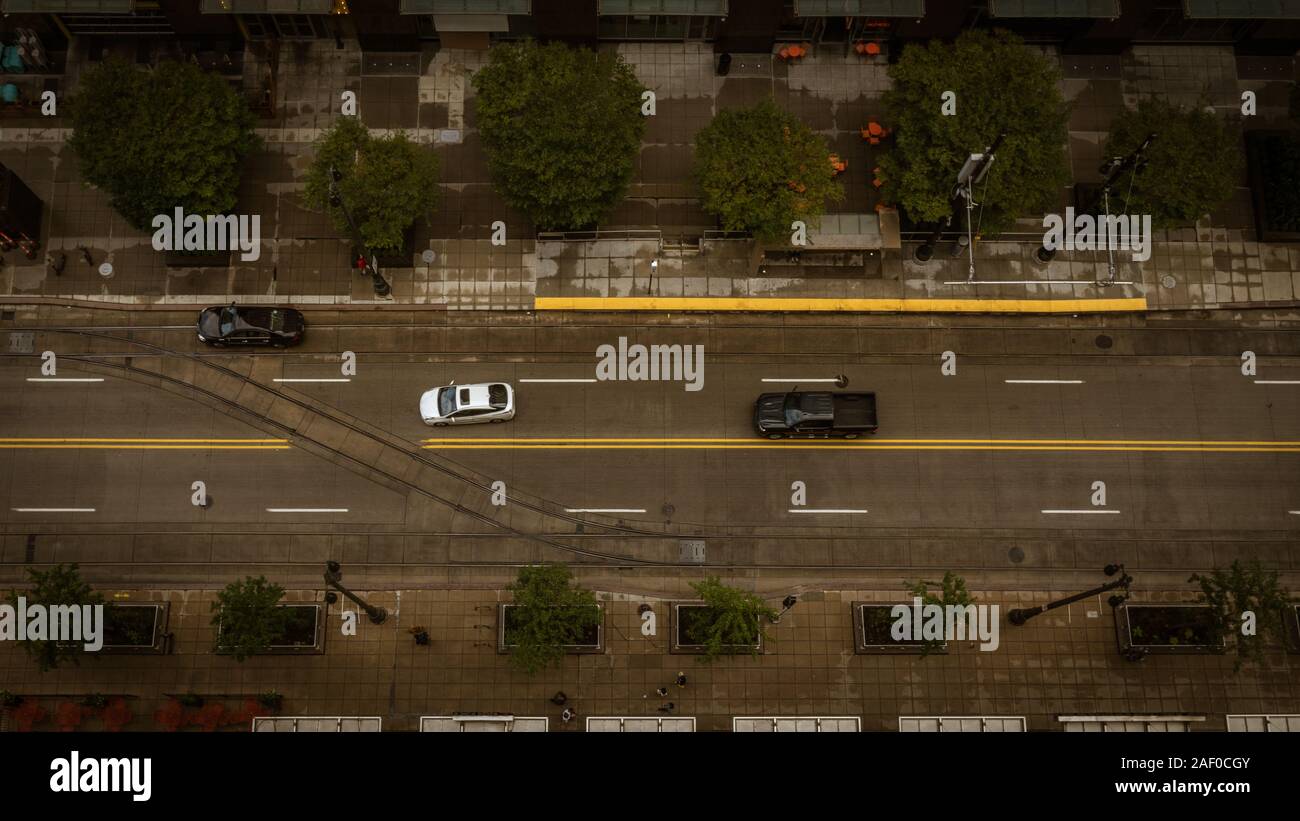 Aerial Top down view of vehicles driving down a city street on a cloudy ...