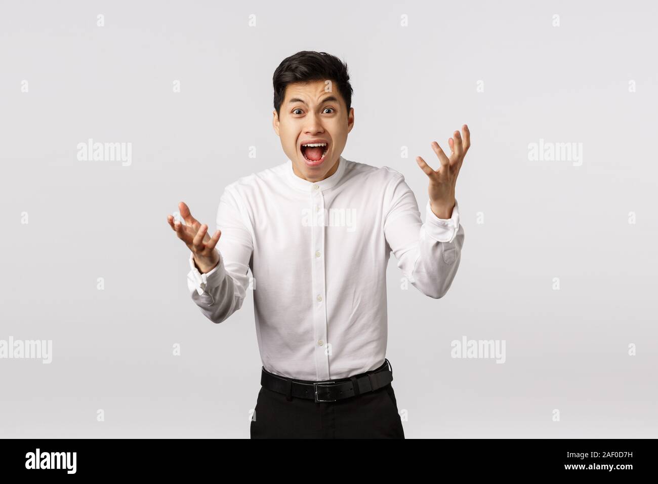 Outraged, alarmed young asian guy screaming what have you done, how ...