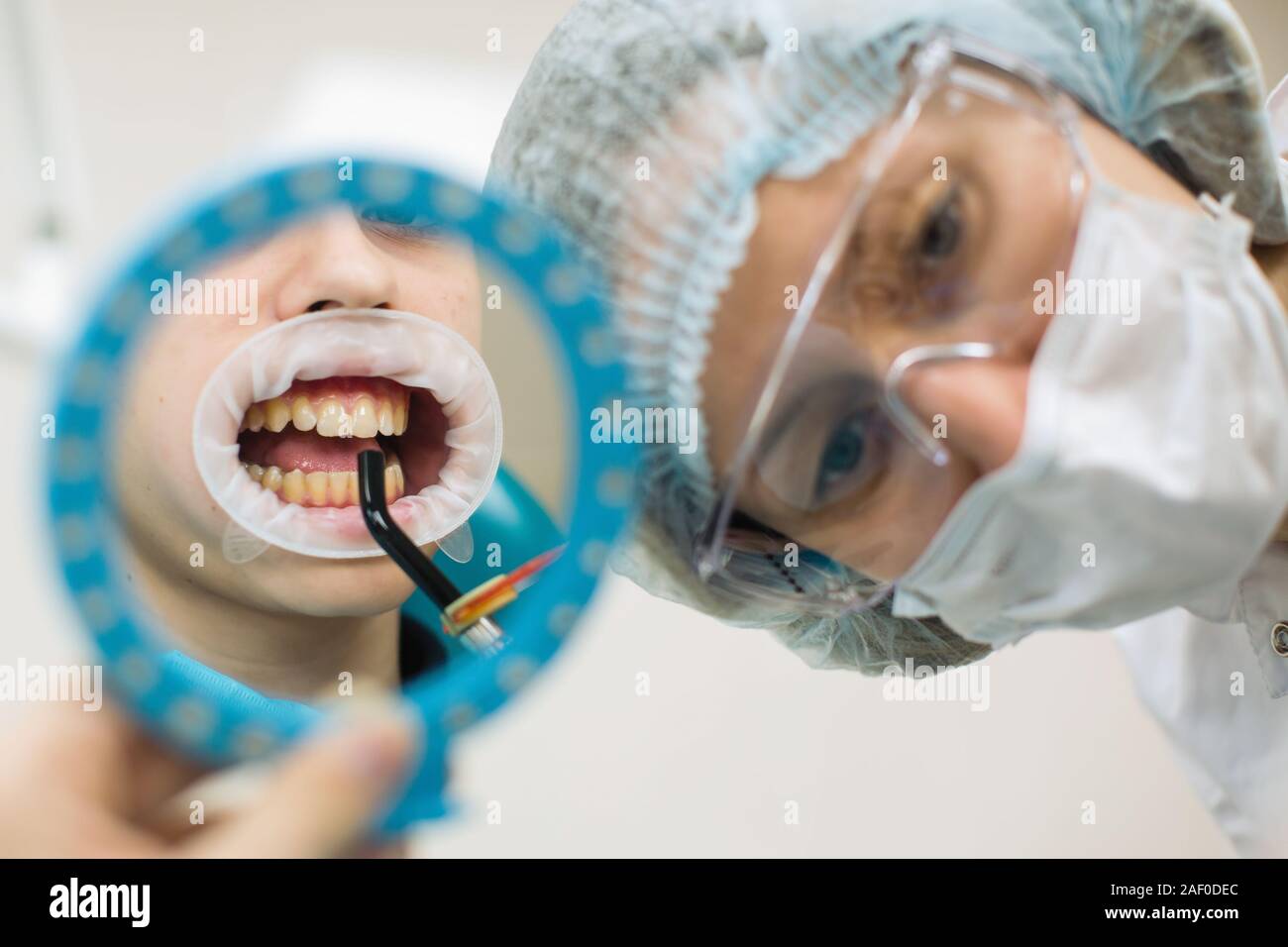 Reflection in the mirror. Woman dentist doing teeth checkup man patient ...