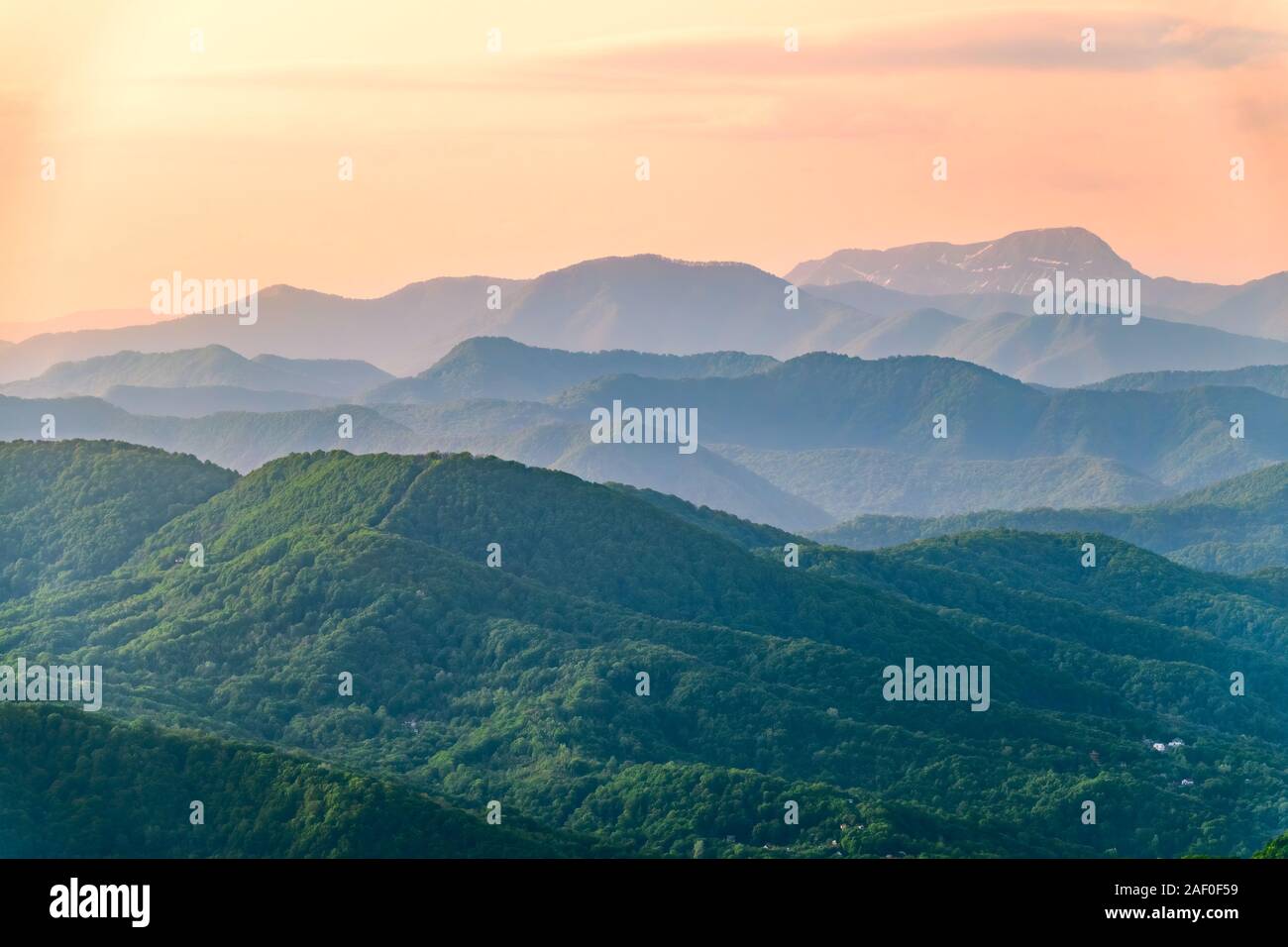 Layers of green mountains and hills in the haze during sunset ...