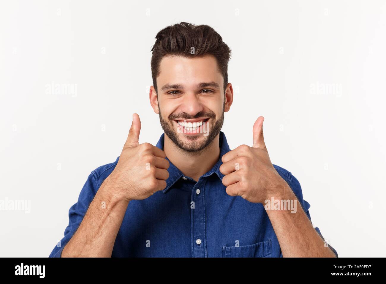 Happy casual young man showing thumb up and smiling isolated on white background Stock Photo - Alamy
