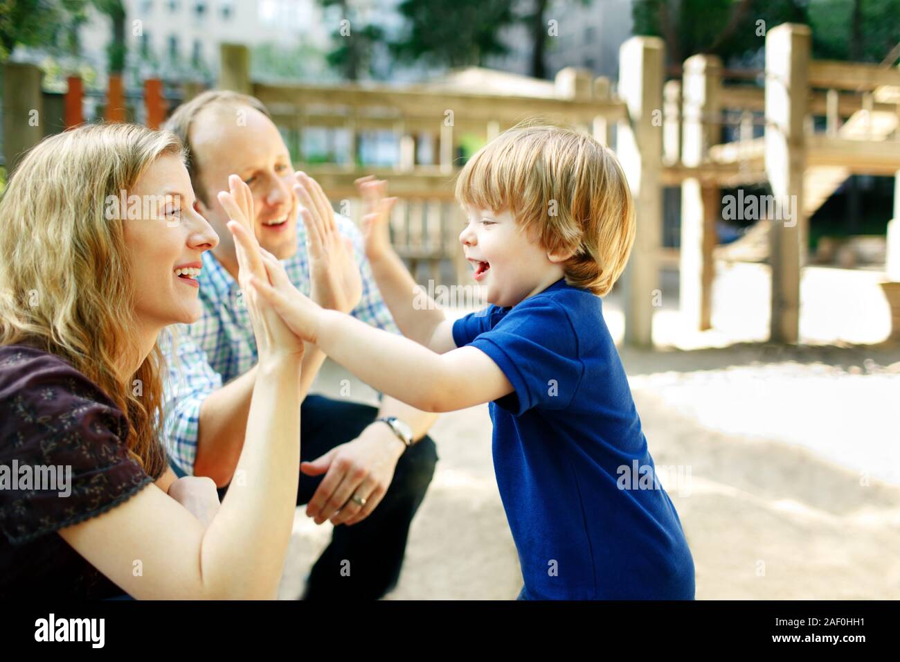 Son giving parents high fives at playground Stock Photo - Alamy