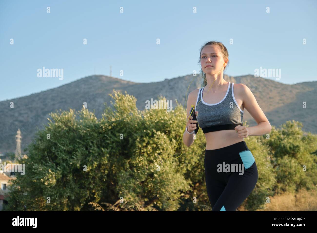 Running young teenager girl in fitness clothes headphones with ...
