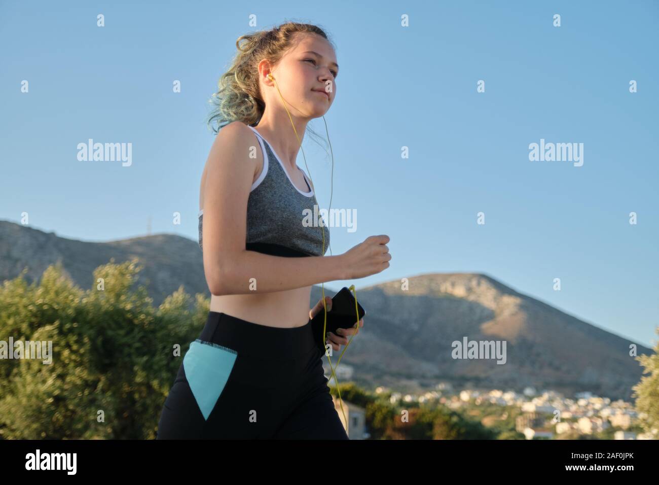 Running young teenager girl in fitness clothes headphones with ...