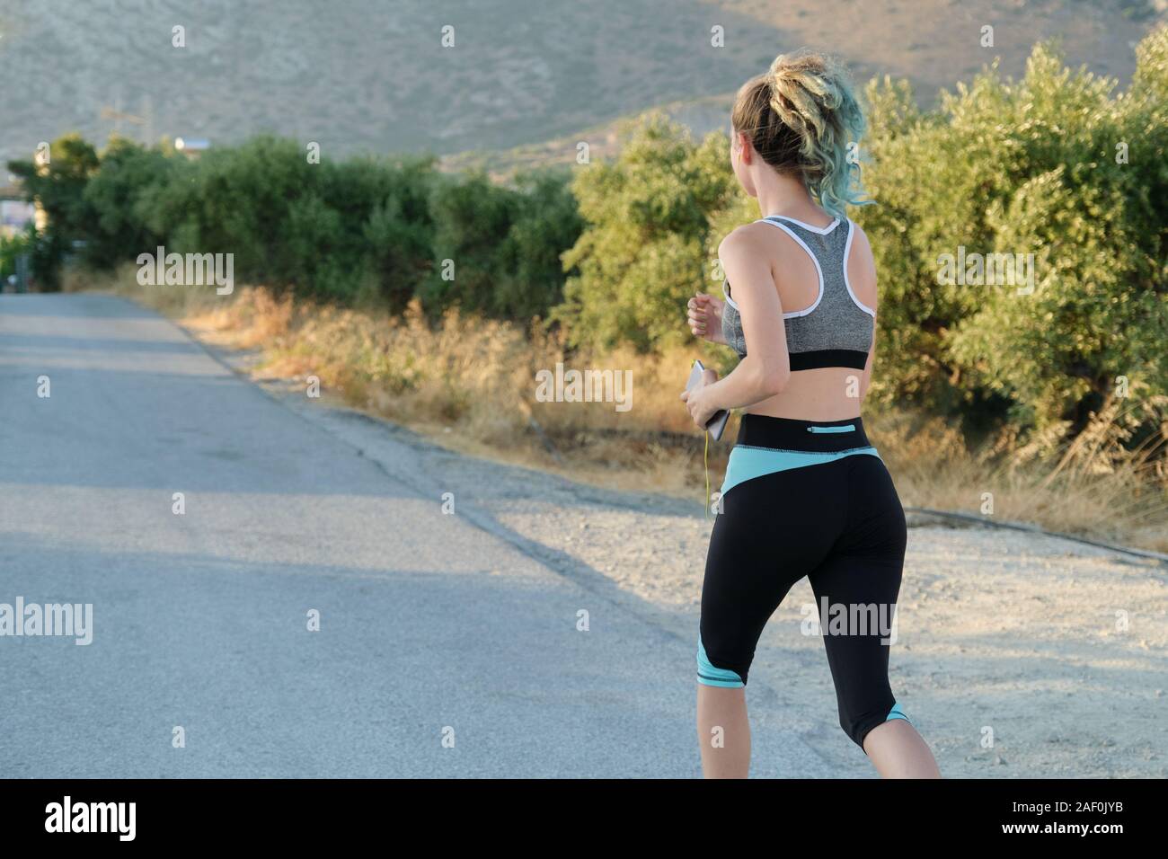 Running fitness girl, road in the mountains, back view, copy space ...