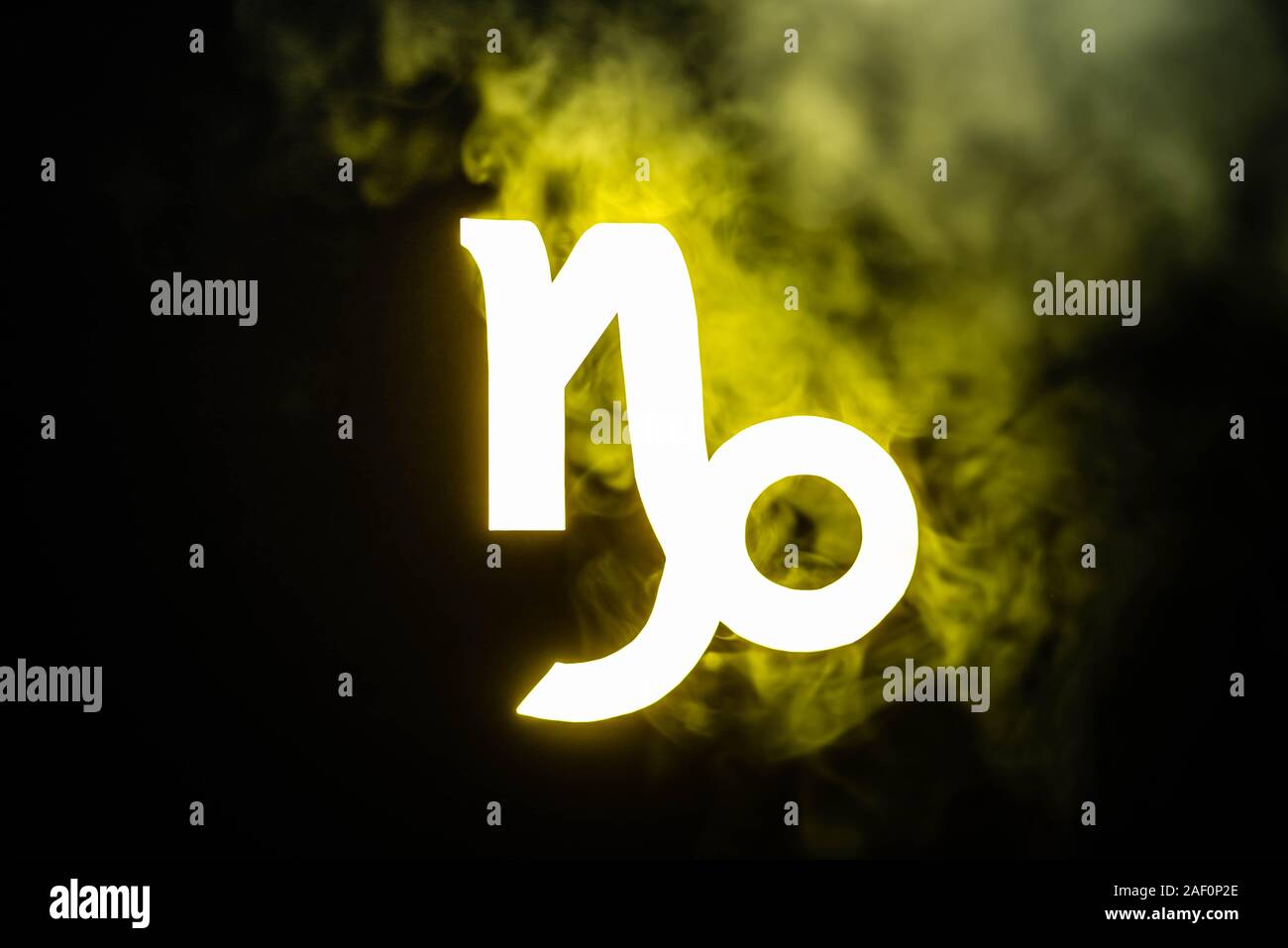 yellow illuminated Capricorn zodiac sign with smoke on background Stock ...