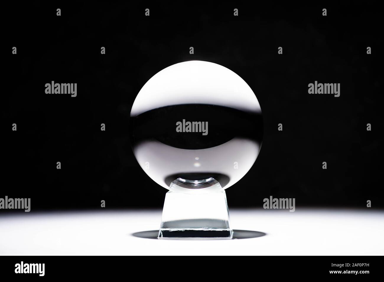 crystal ball on white surface on black background Stock Photo - Alamy