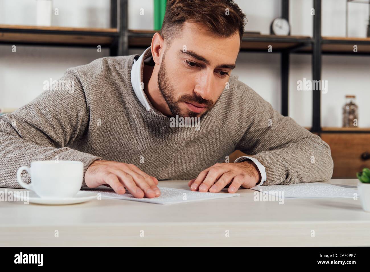 Blind man reading braille font beside coffee at table Stock Photo - Alamy