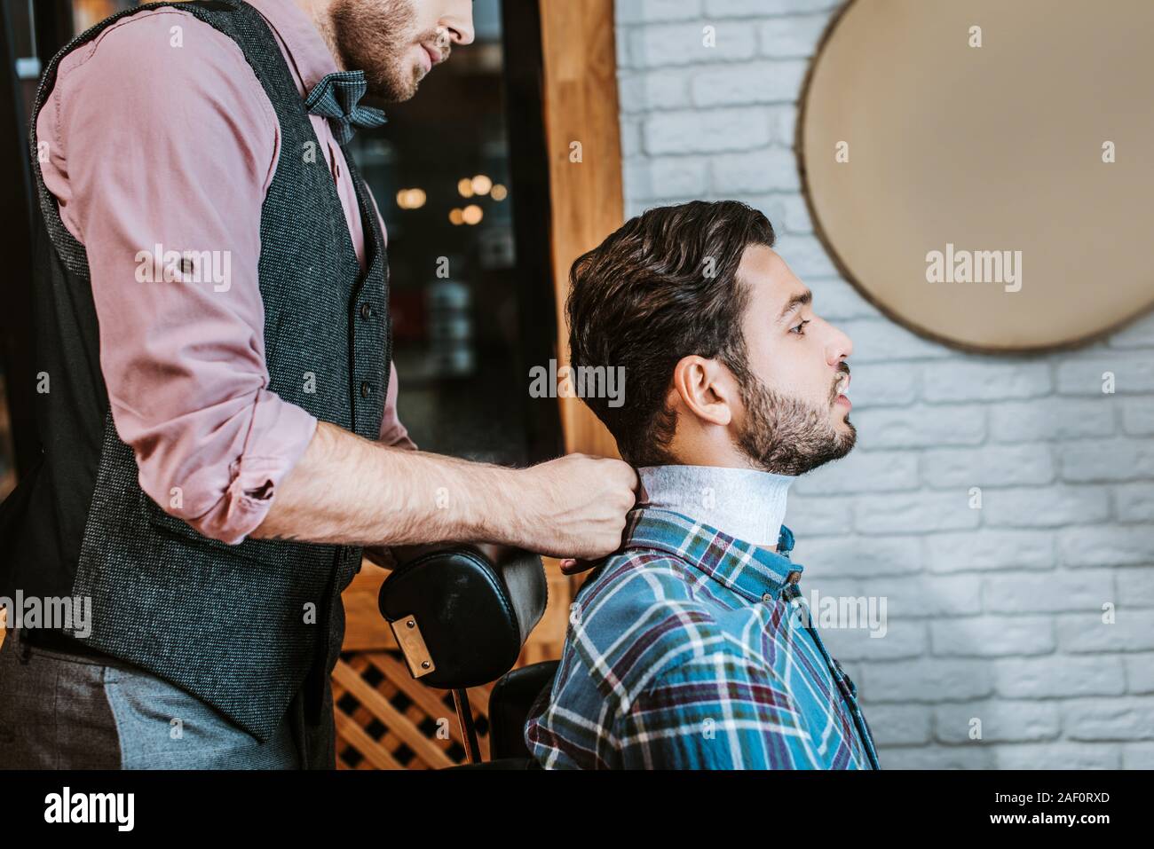 side view of barber fixing collar around neck of happy man Stock Photo ...