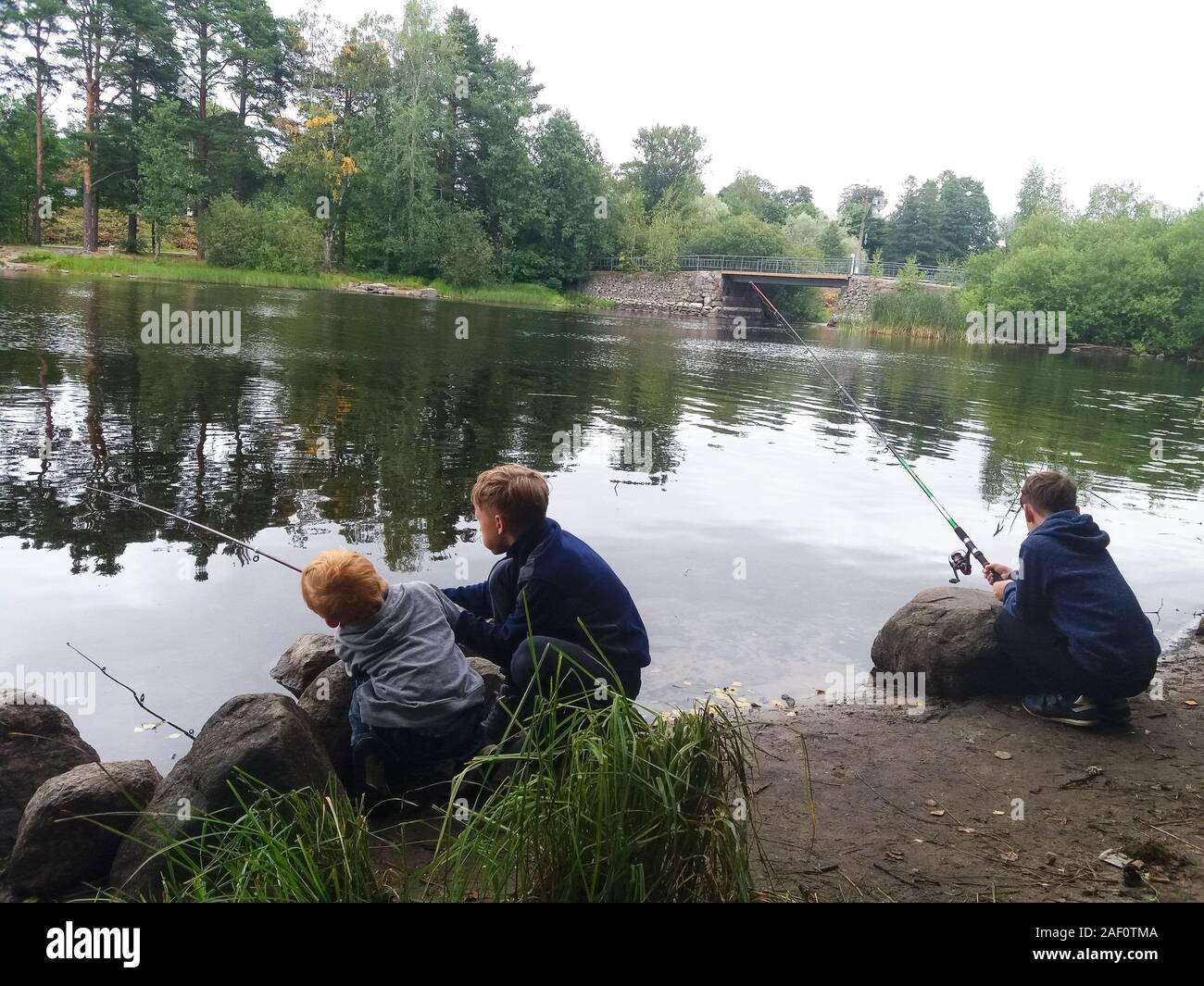 Three boys of different ages - brothers - fish for fishing at a boat ...