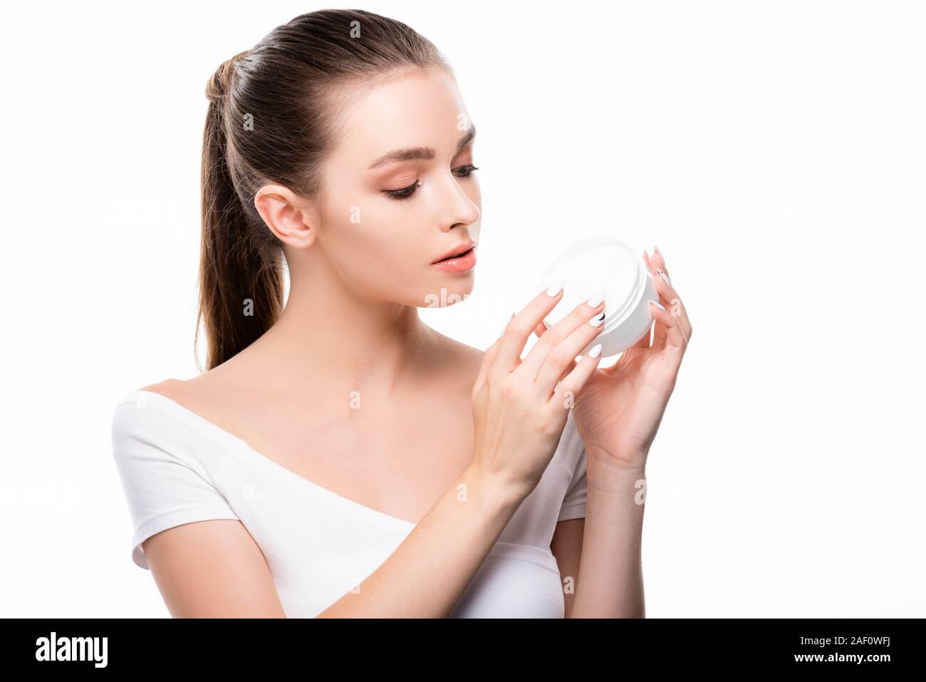 attractive young woman touching face cream in container isolated on ...
