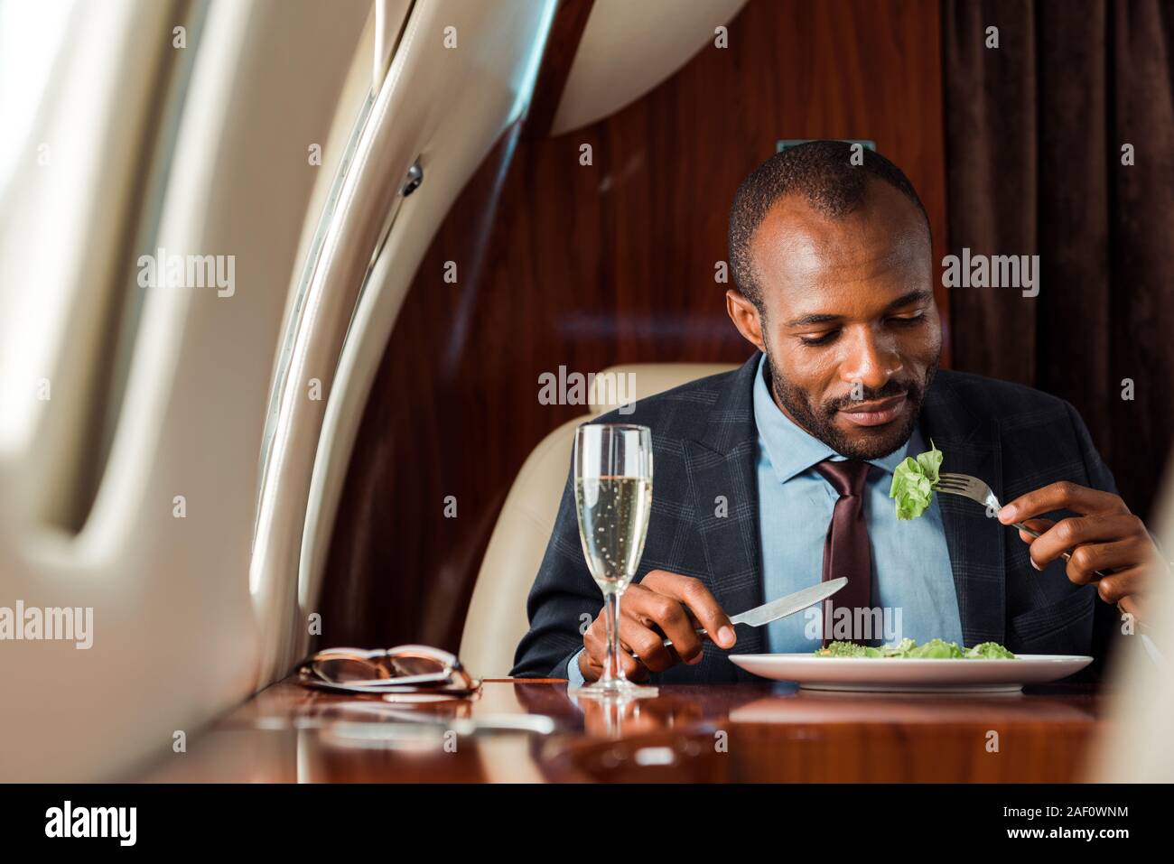 handsome african american businessman eating salad in private jet Stock ...