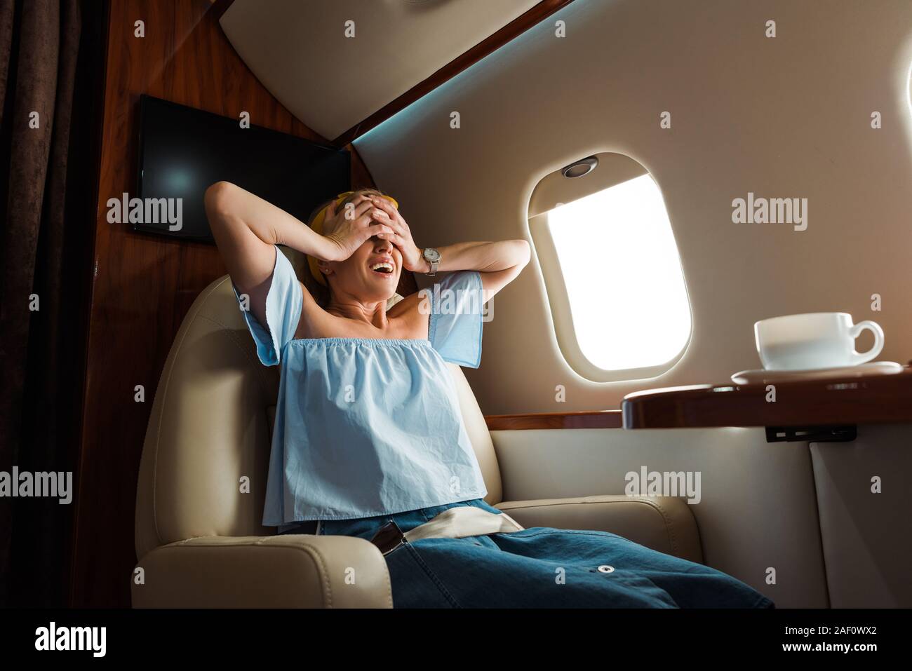 scared woman with fear of flight covering eyes during flight in private ...