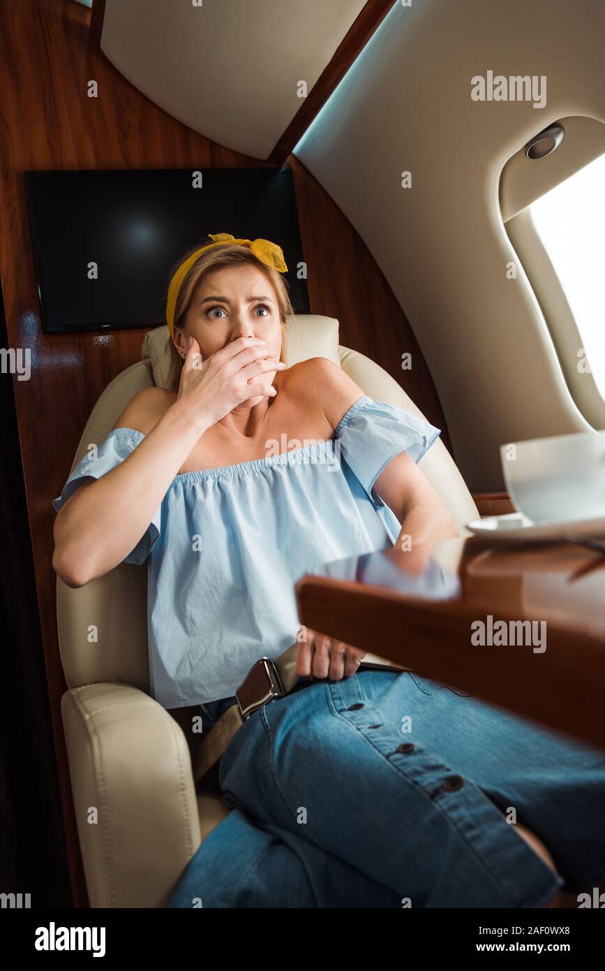selective focus of scared woman with fear of flight covering mouth ...