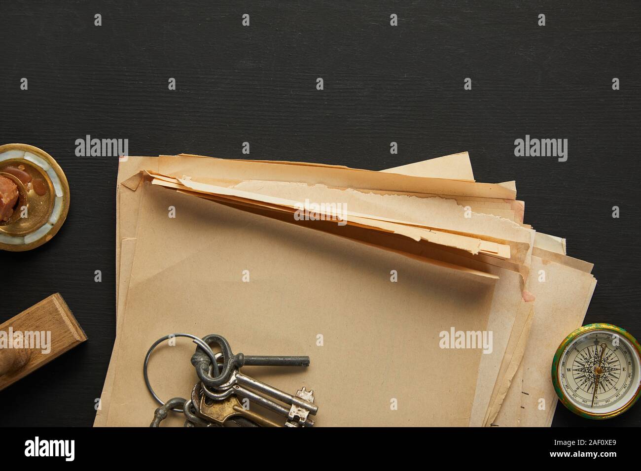 top view of vintage paper, keys, compass and stamp on black background ...