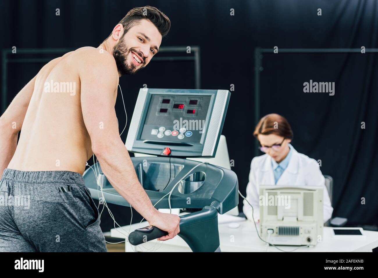 doctor conducting endurance test with smiling sportsman in gym Stock ...