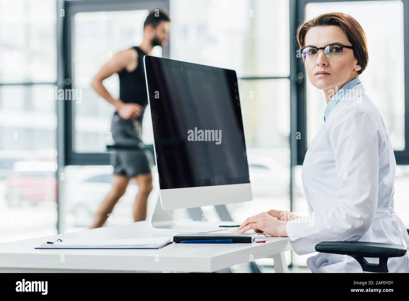 selective focus of beautiful doctor sitting near computer with blank ...