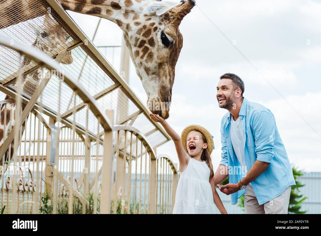 selective focus of cheerful man and kid with closed eyes feeding ...
