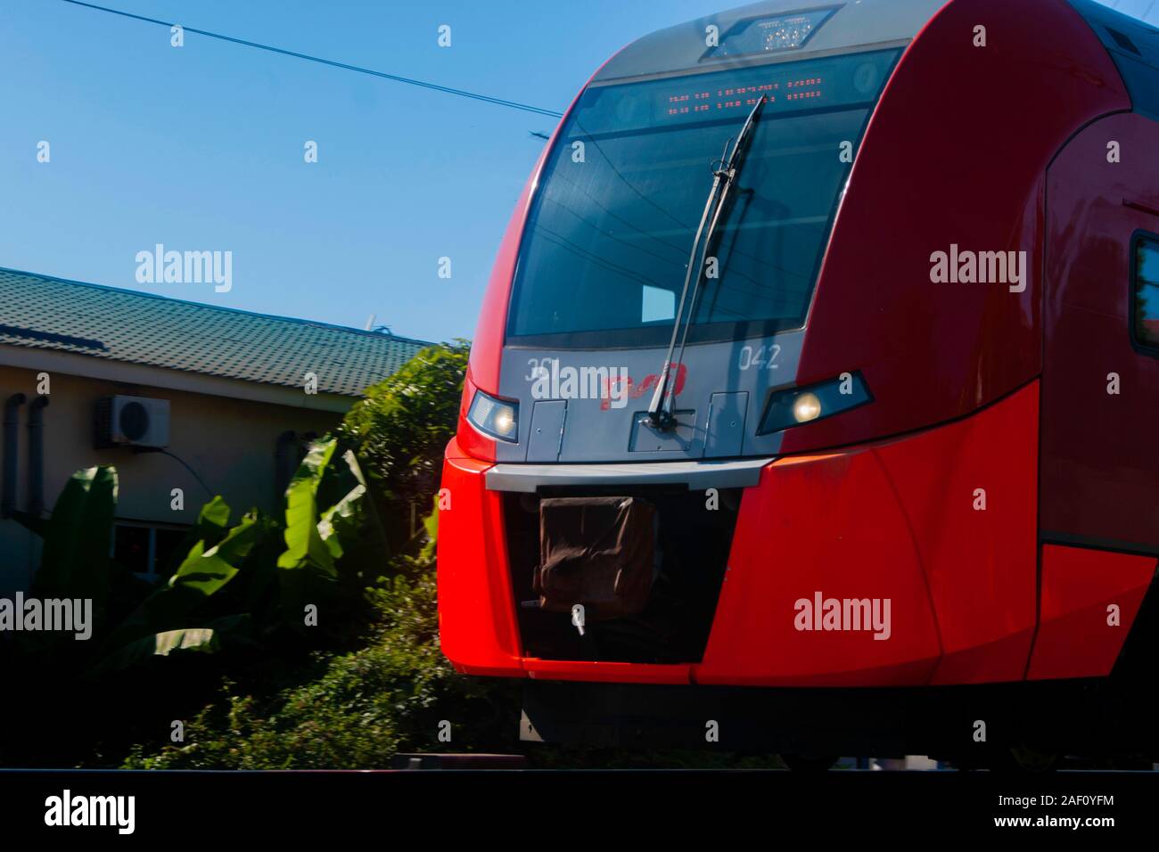 The red-grey train sweeps through the resort town, the sky is reflected ...