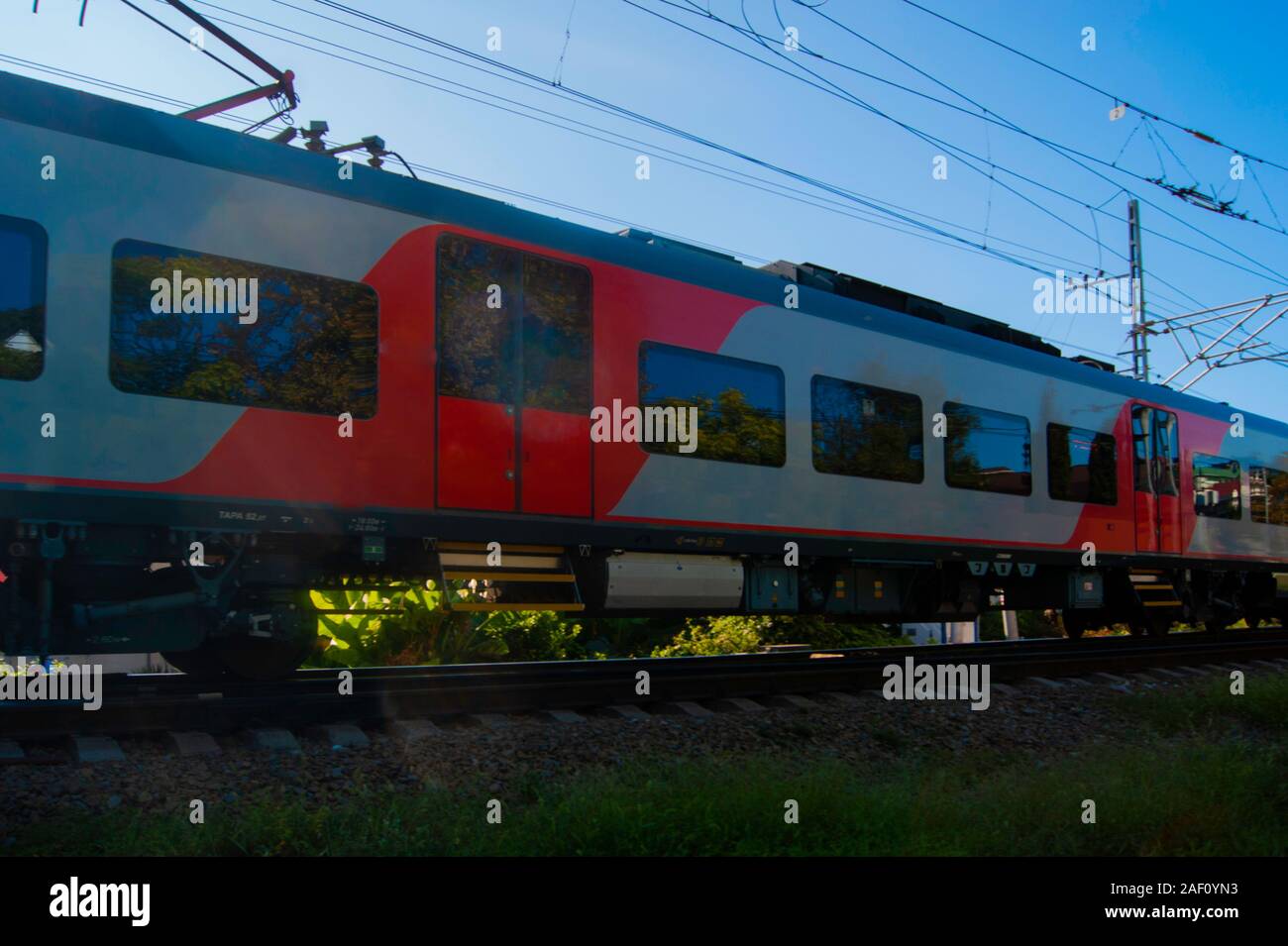 The red-grey train sweeps through the resort town, the sky is reflected ...