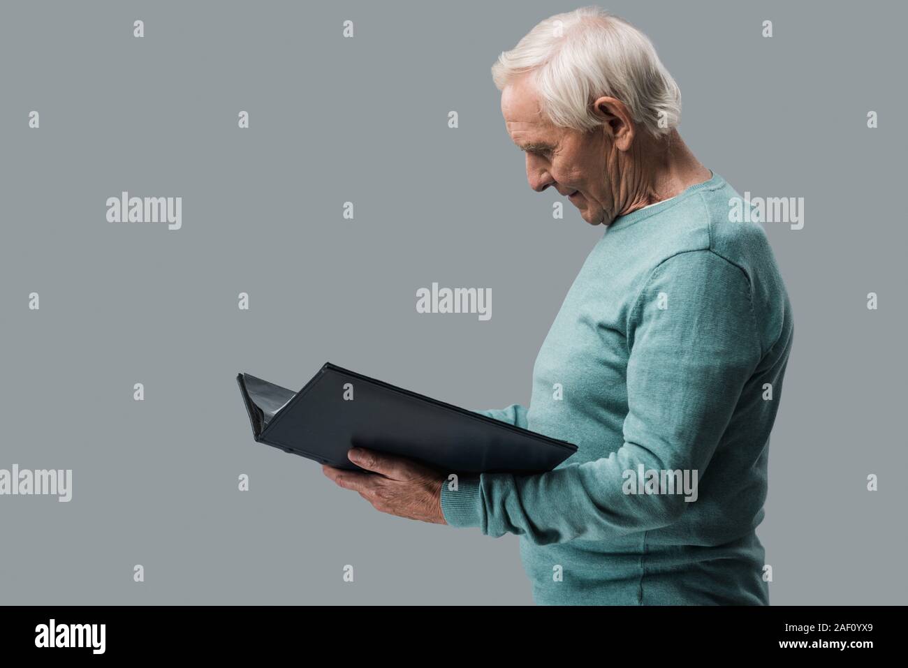 happy retired man with grey hair looking at photo album isolated on ...