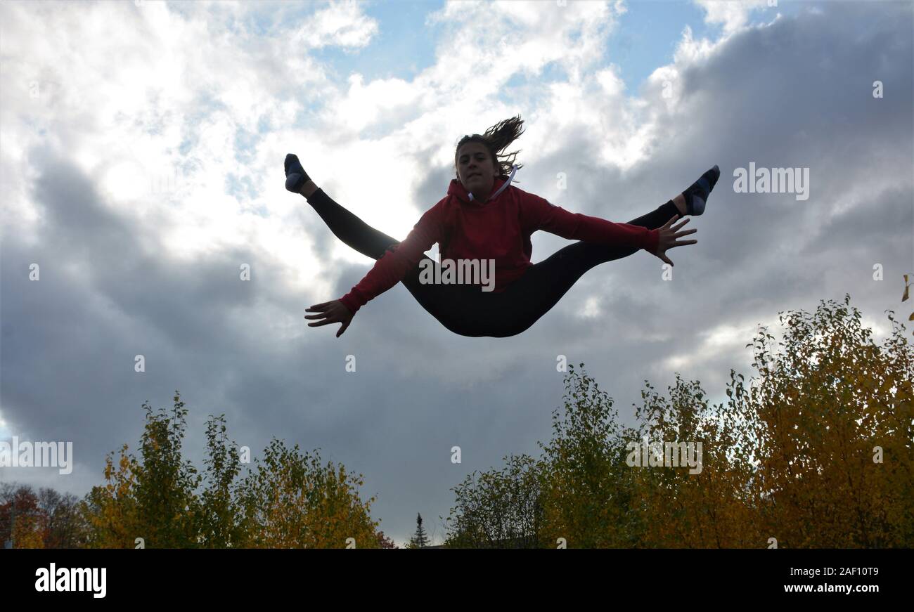 Teenage girl doing acrobatics on trampoline Stock Photo - Alamy