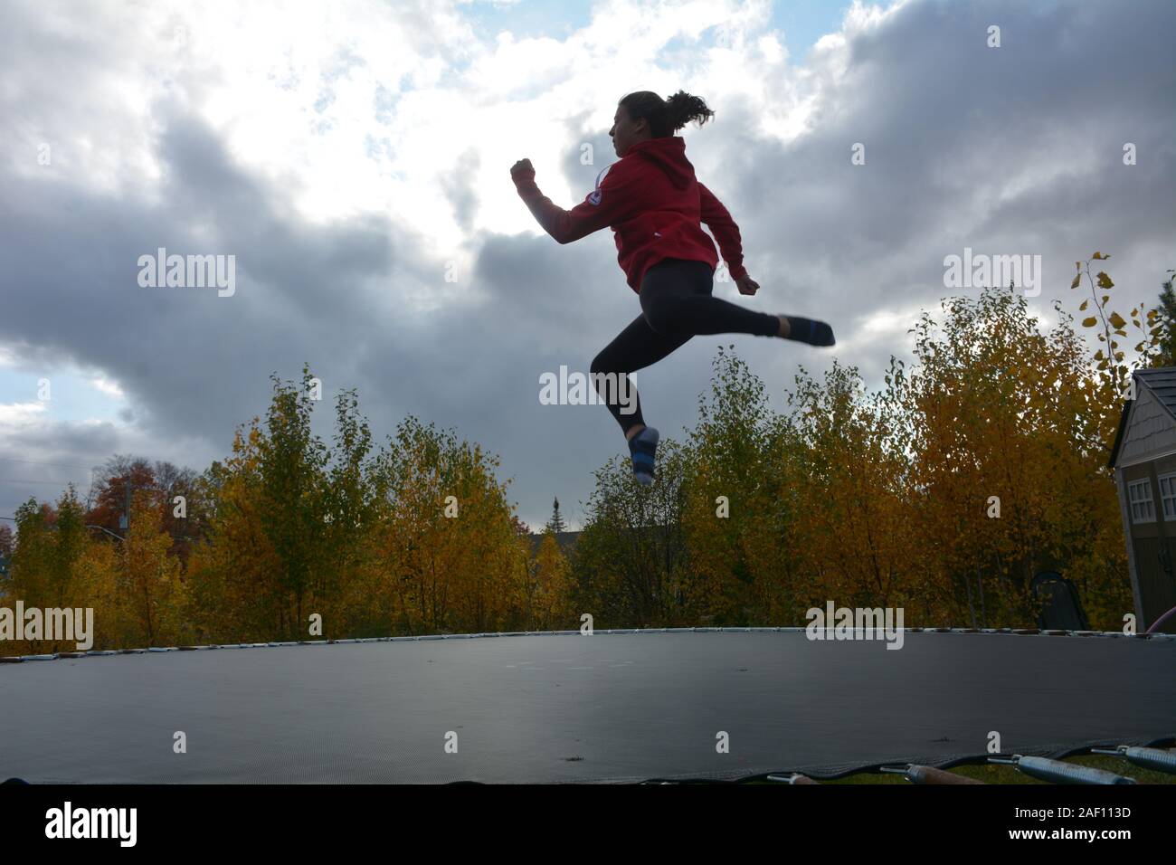 Teenage girl doing acrobatics on trampoline Stock Photo - Alamy