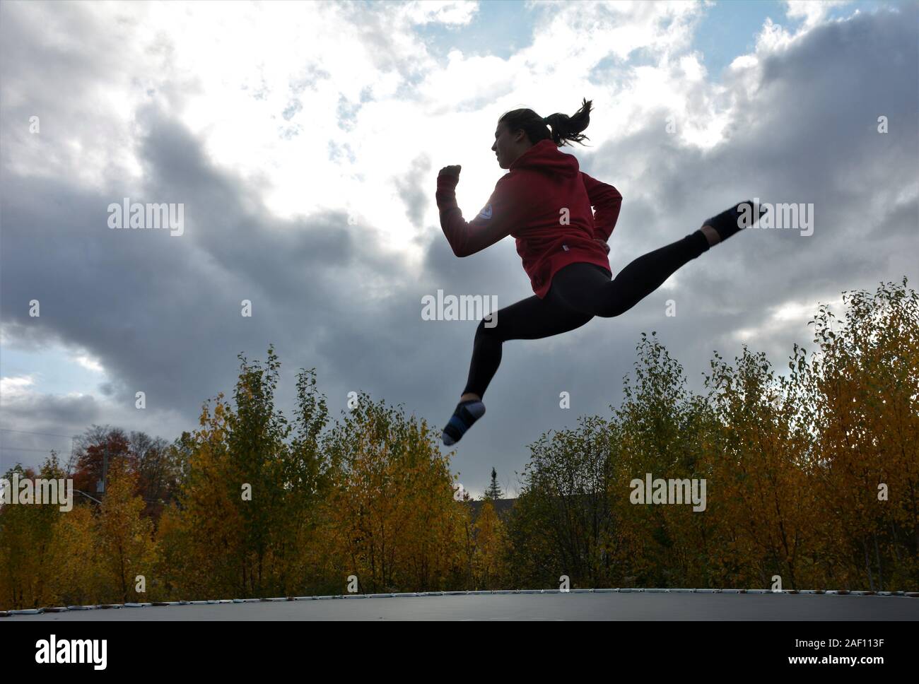 Teenage girl doing acrobatics on trampoline Stock Photo - Alamy