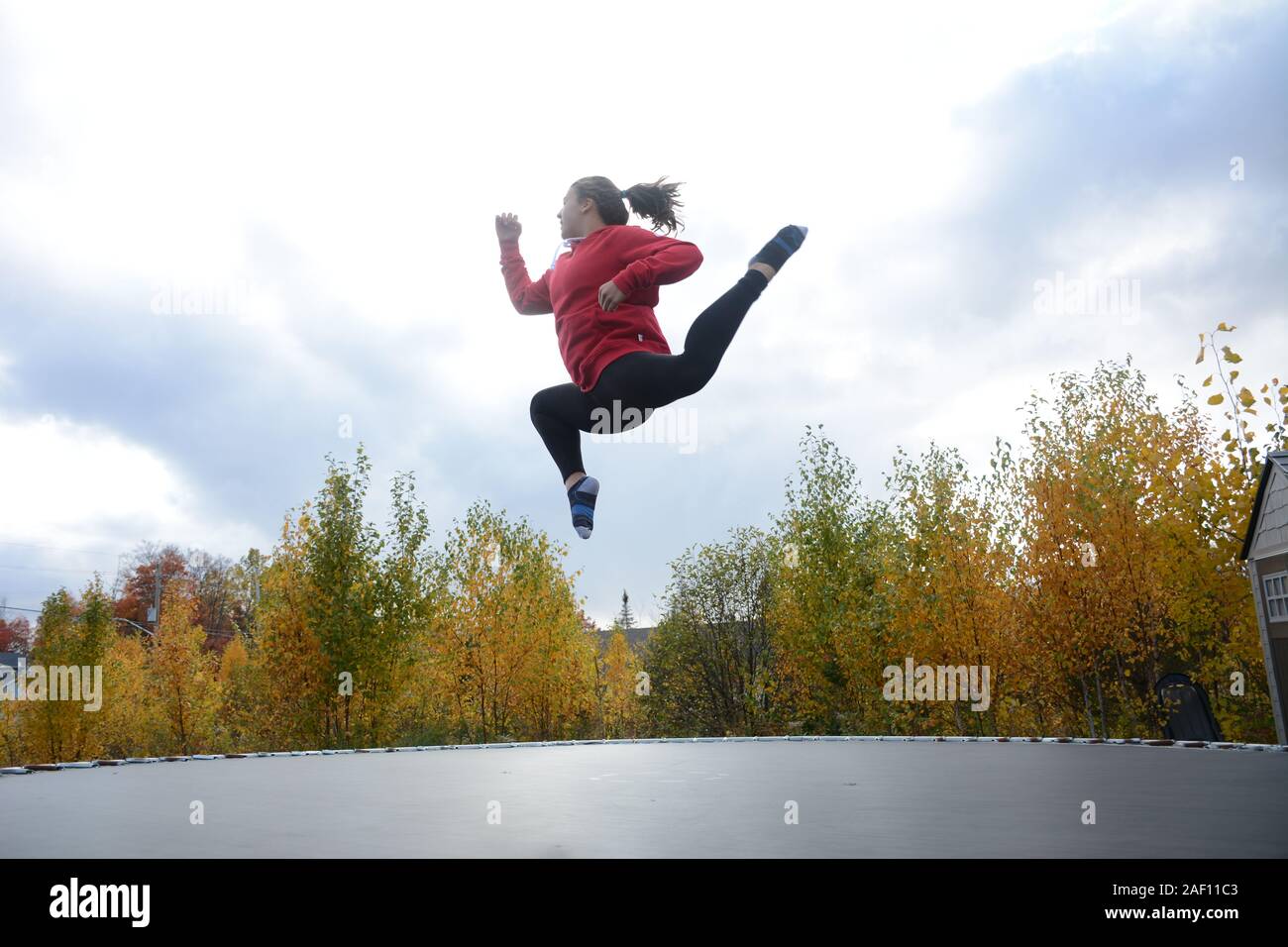 Teenage girl doing acrobatics on trampoline Stock Photo - Alamy