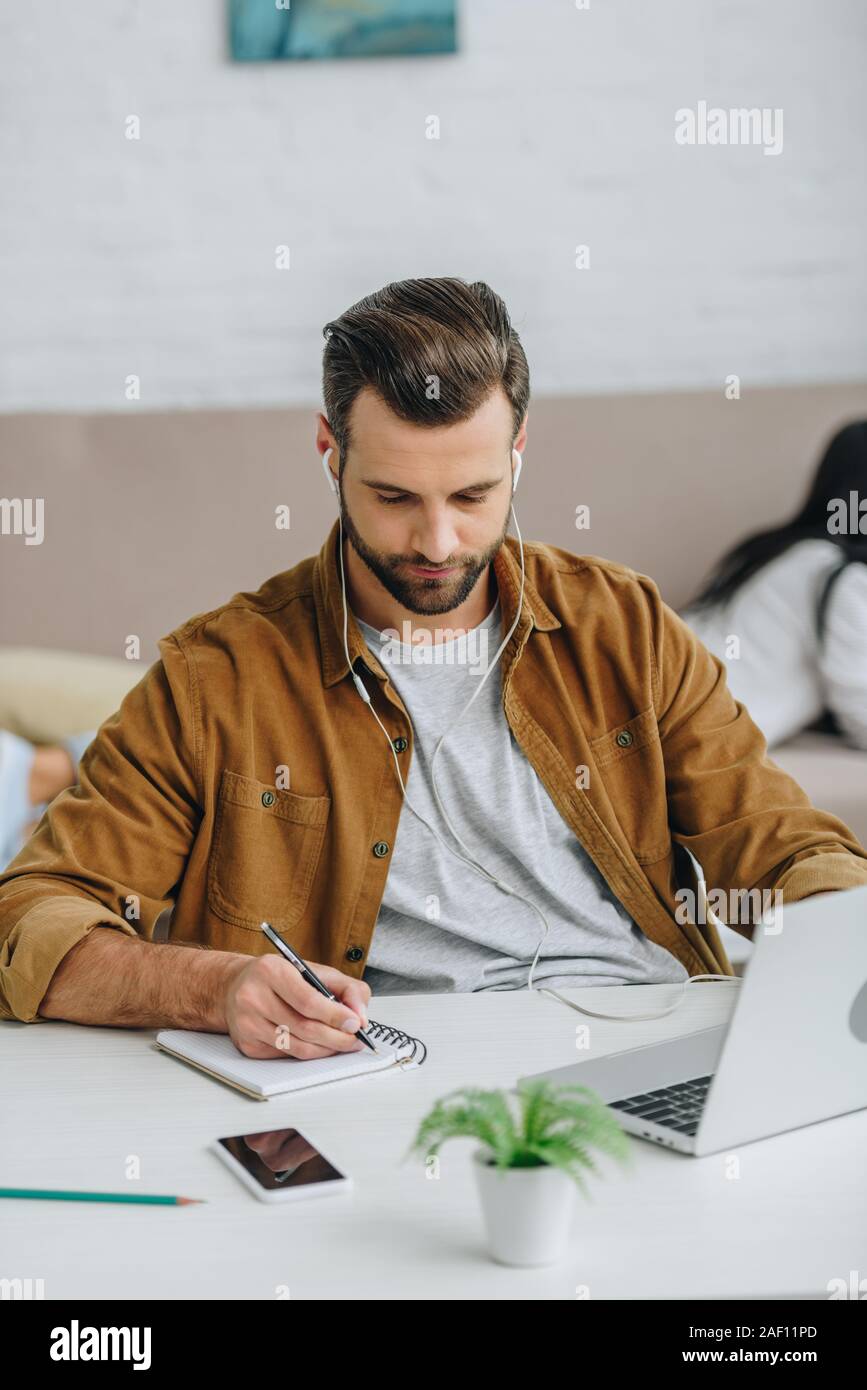 handsome man writing in notebook with pen and listening music Stock ...