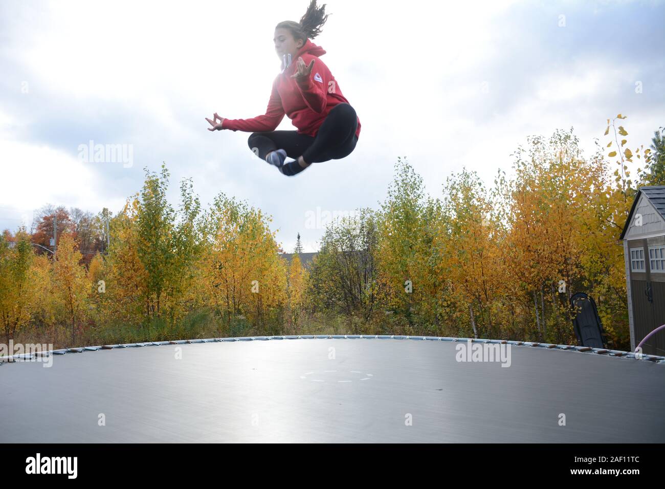 Teenage girl doing acrobatics on trampoline Stock Photo - Alamy
