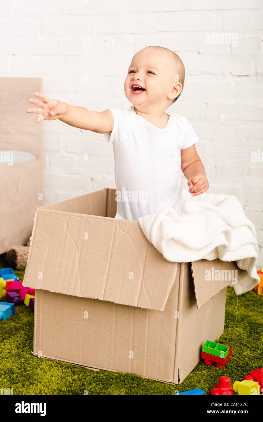 Happy little child standing in cardboard box and raising hand Stock ...