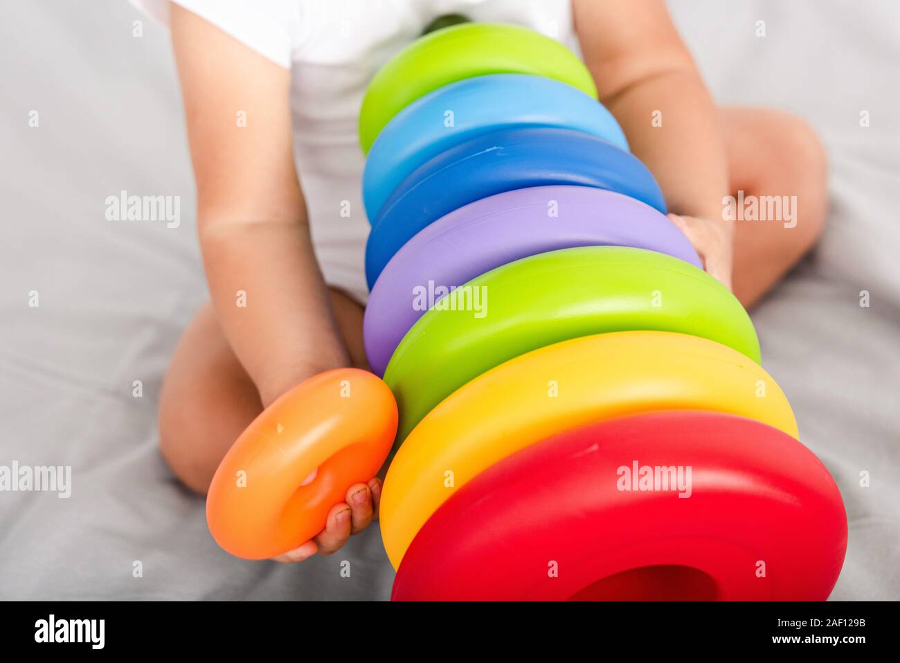 Cropped view of barefoot child in white clothes sitting on bed and ...
