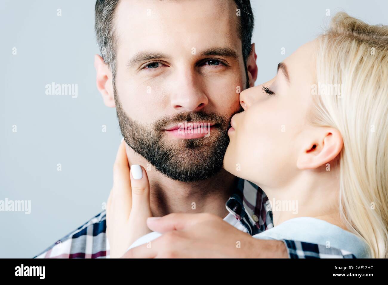 beautiful blonde girl kissing handsome man isolated on grey Stock Photo ...