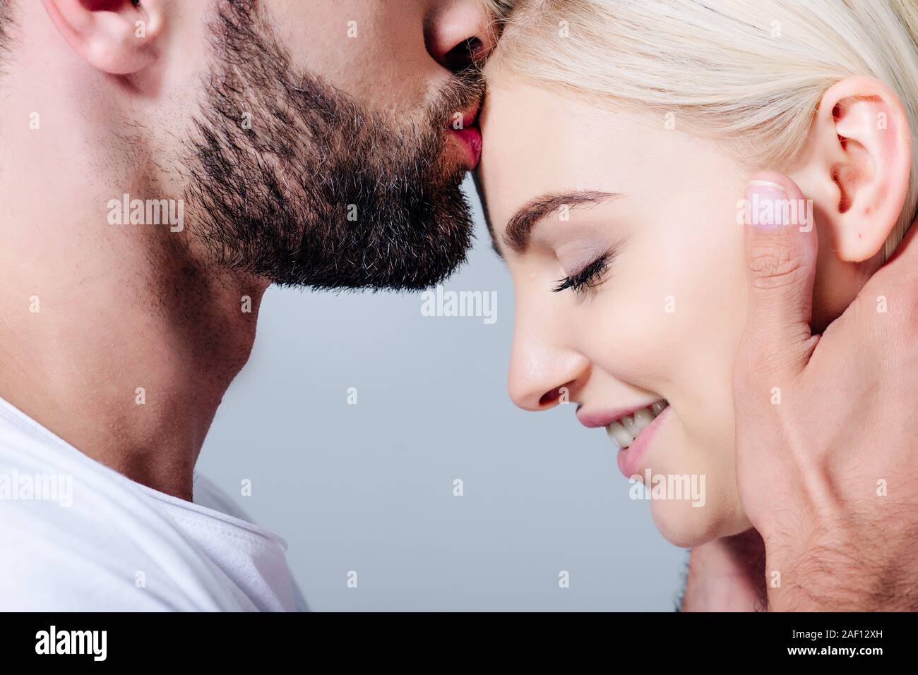 man kissing on forehead beautiful smiling girl isolated on grey Stock ...