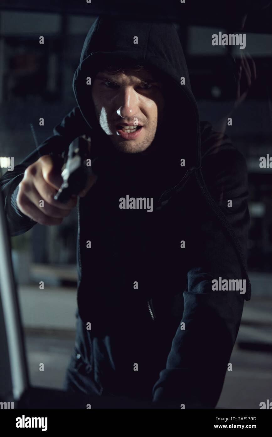 aggressive thief in black hoodie pointing gun at car window Stock Photo ...
