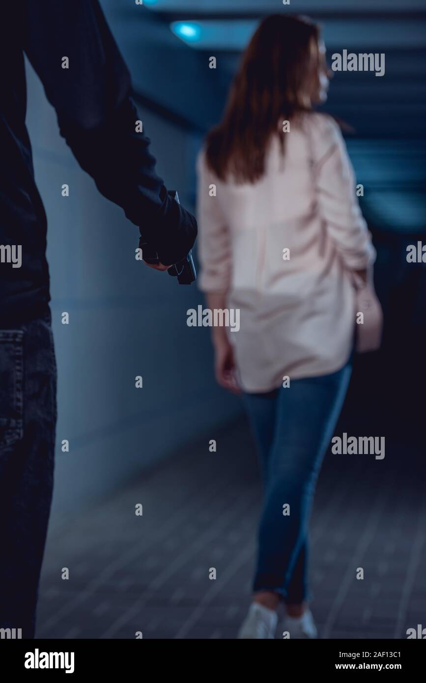 robber holding gun behind walking woman in underpass Stock Photo - Alamy
