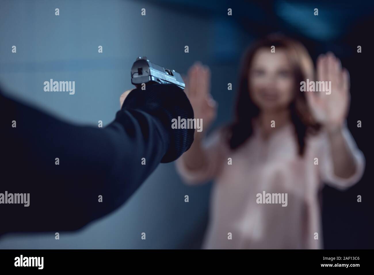 selective focus of robber pointing gun at woman with raised hands Stock ...
