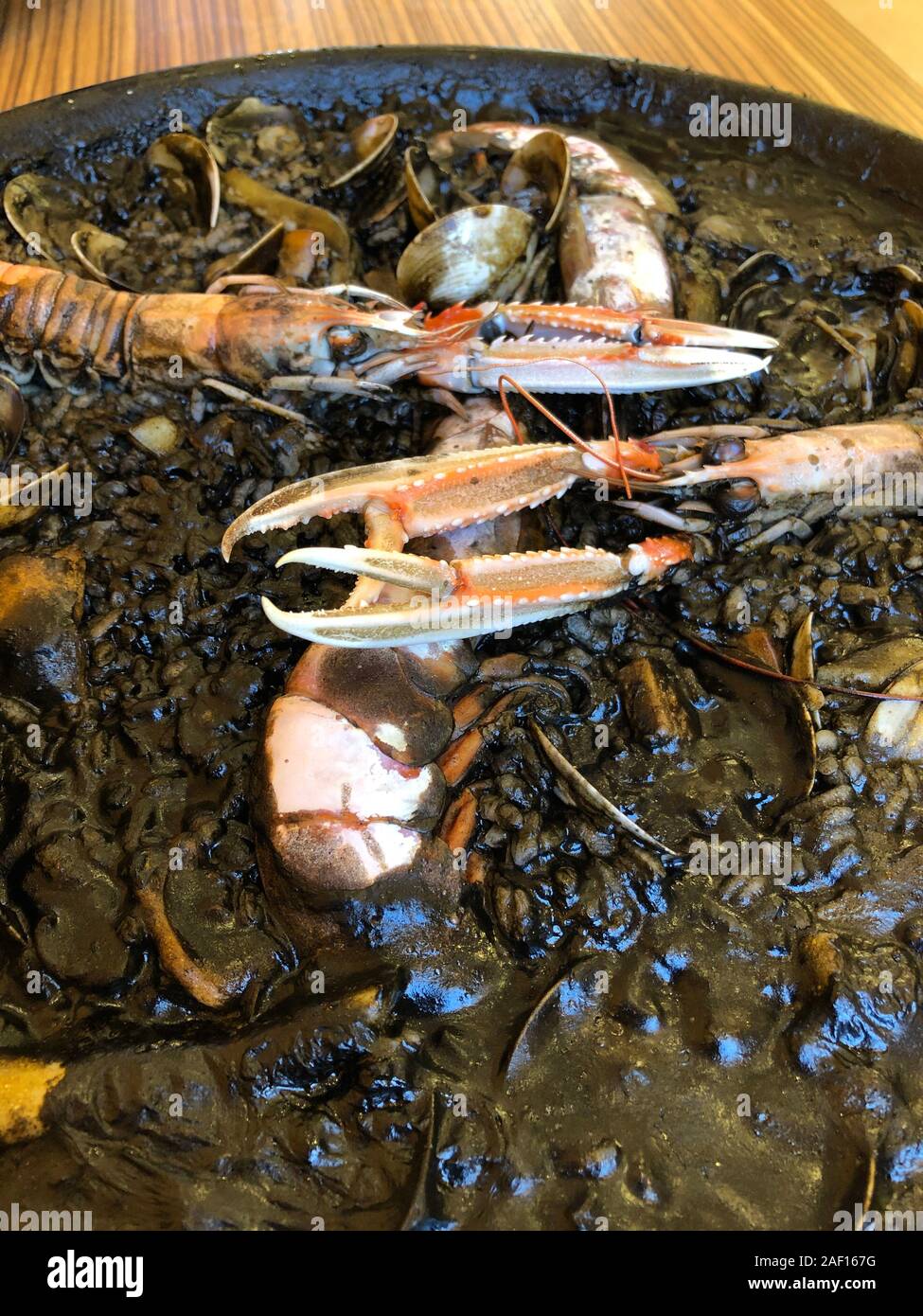 Arroz negro (Spanish squid ink rice) cooked in a big flat pan with ...