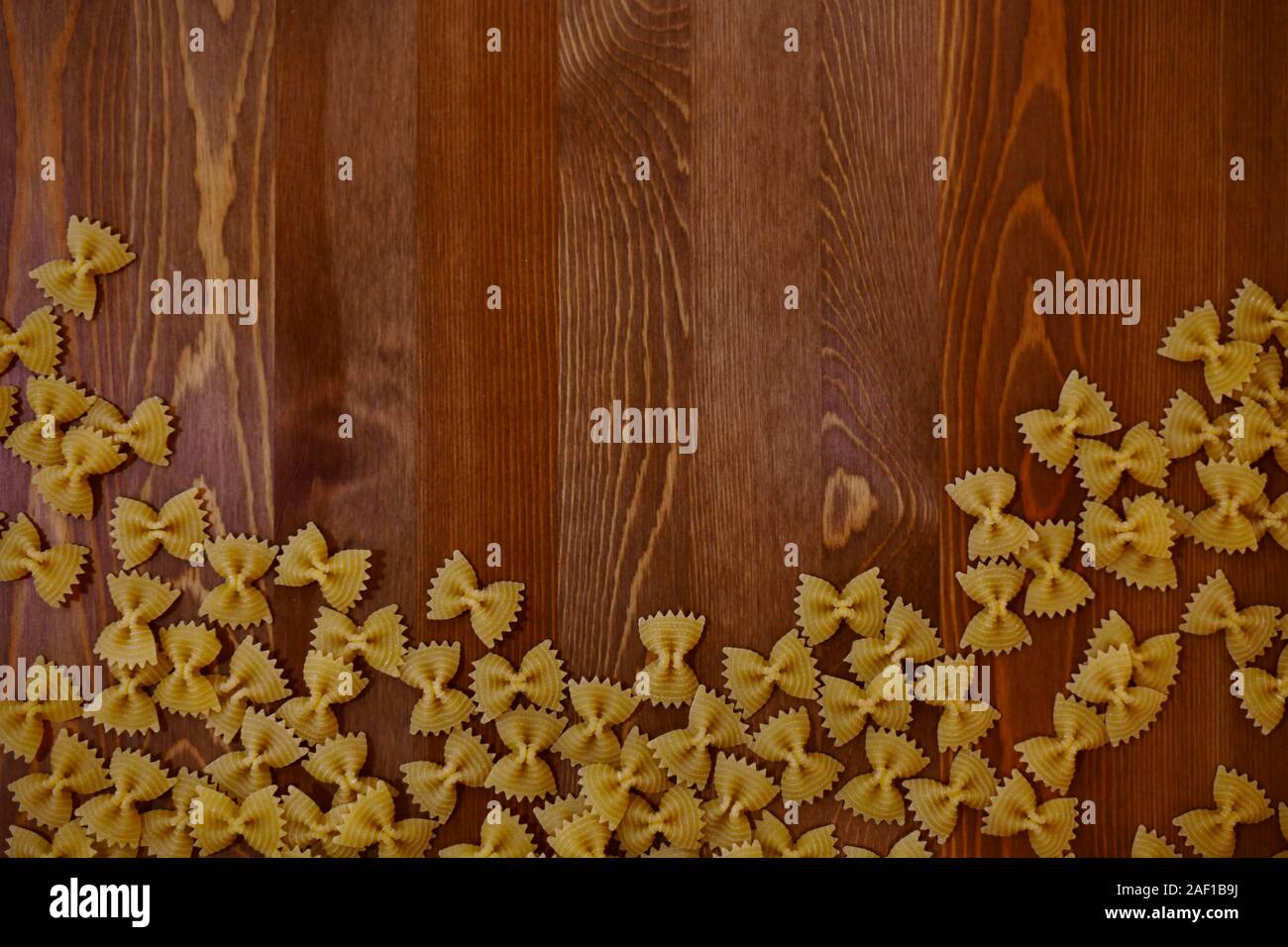 Pasta bows filling the lower corners of a wooden background, in a ...